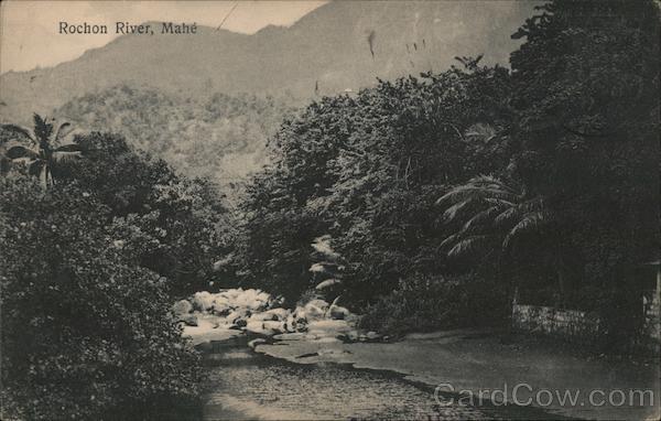 Waterfall and river rapids surrounded by palm trees with a mountain in ...